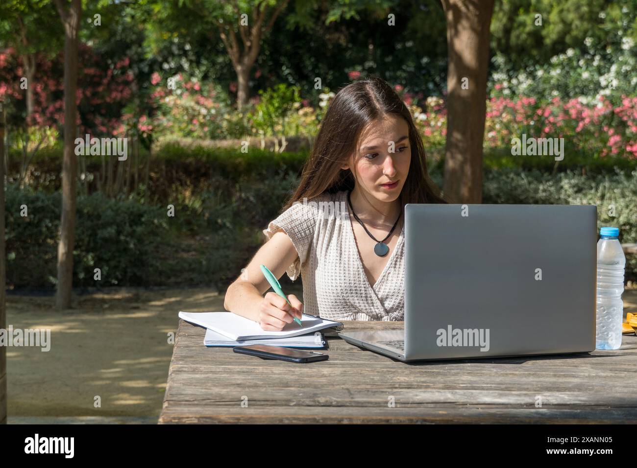 Attentive college girl taking notes and using her laptop at a table on ...