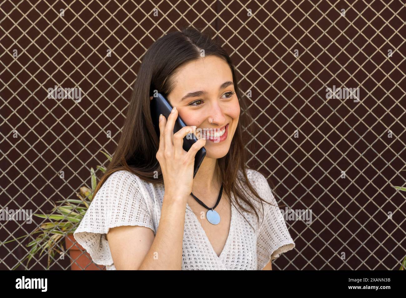 College girl smiles while talking on her smartphone, enjoying the ...