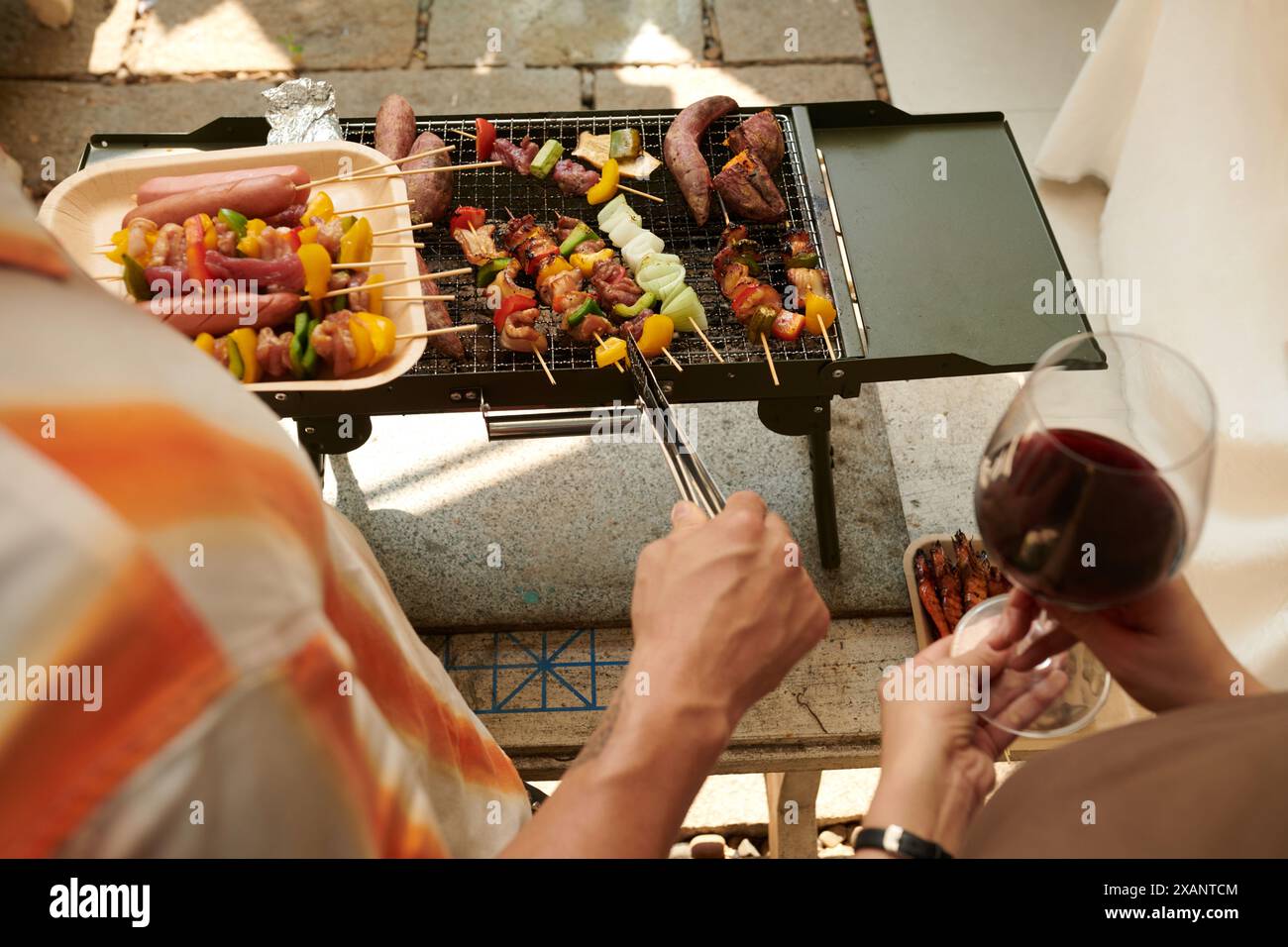 Couple drinking wine and cooking kebabs in backyard Stock Photo - Alamy