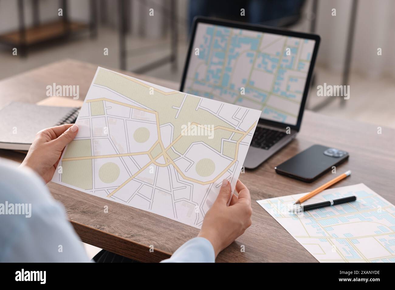 Cartographer working with cadastral maps at wooden table in office ...