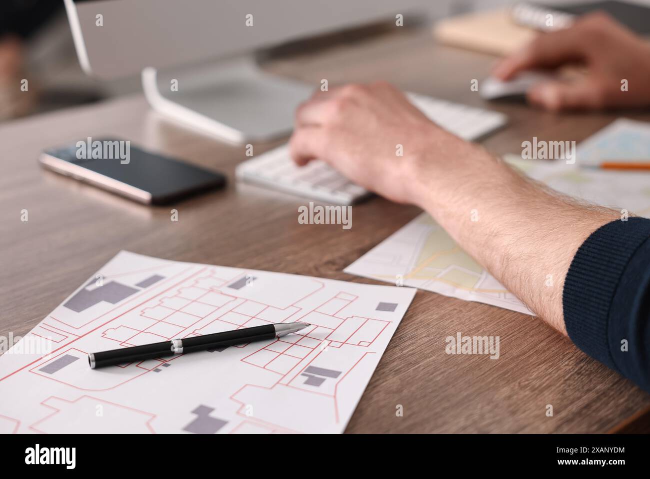Cartographer working with cadastral maps at wooden table in office ...