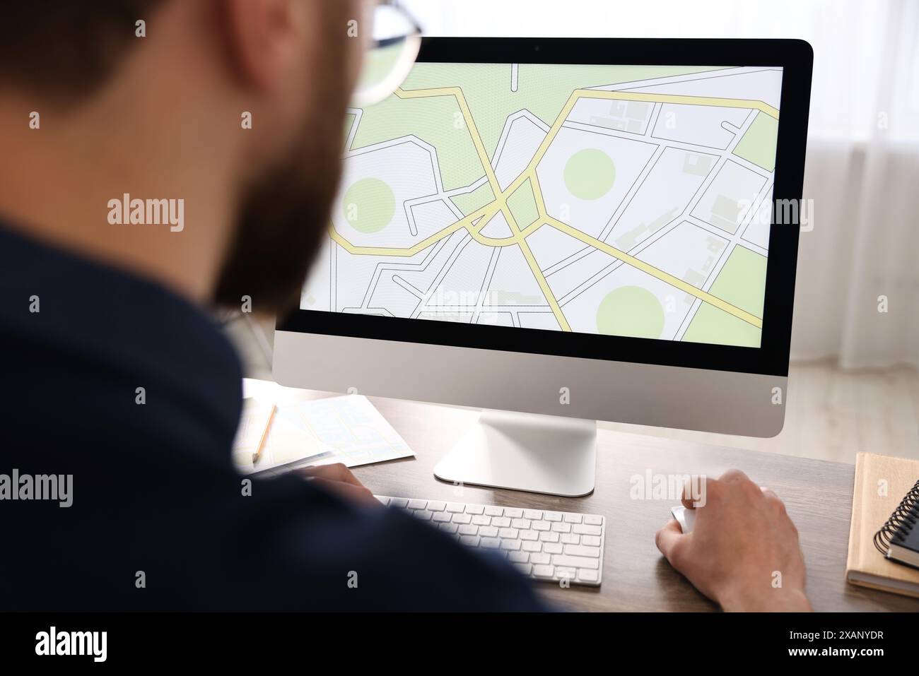 Cartographer working with cadastral map on computer at table in office ...