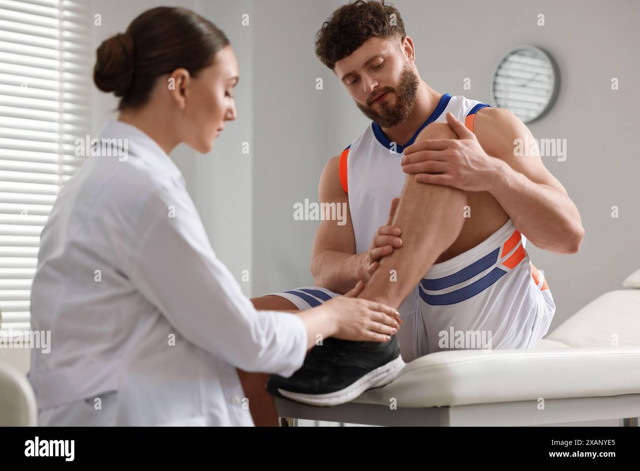 Sports injury. Doctor examining patient's leg in hospital Stock Photo ...