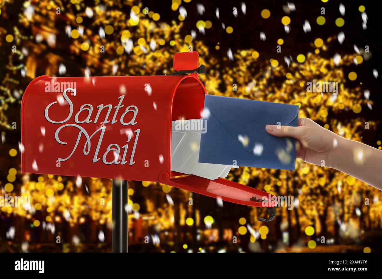 Woman putting letter to Santa Claus into mail box under falling snow ...