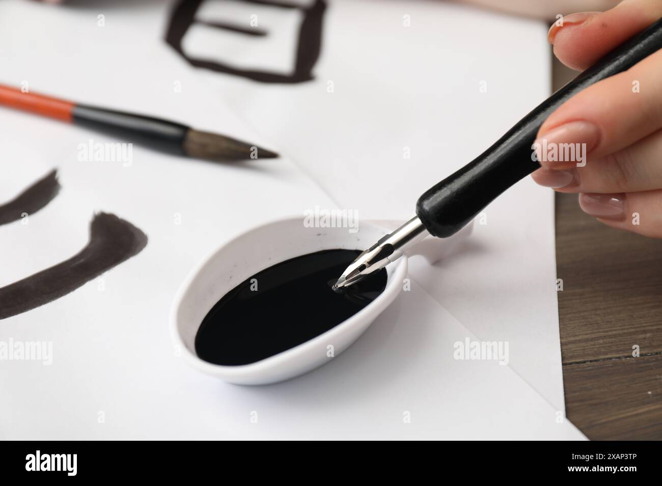 Calligraphy. Woman dipping brush into inkwell at table, closeup Stock ...