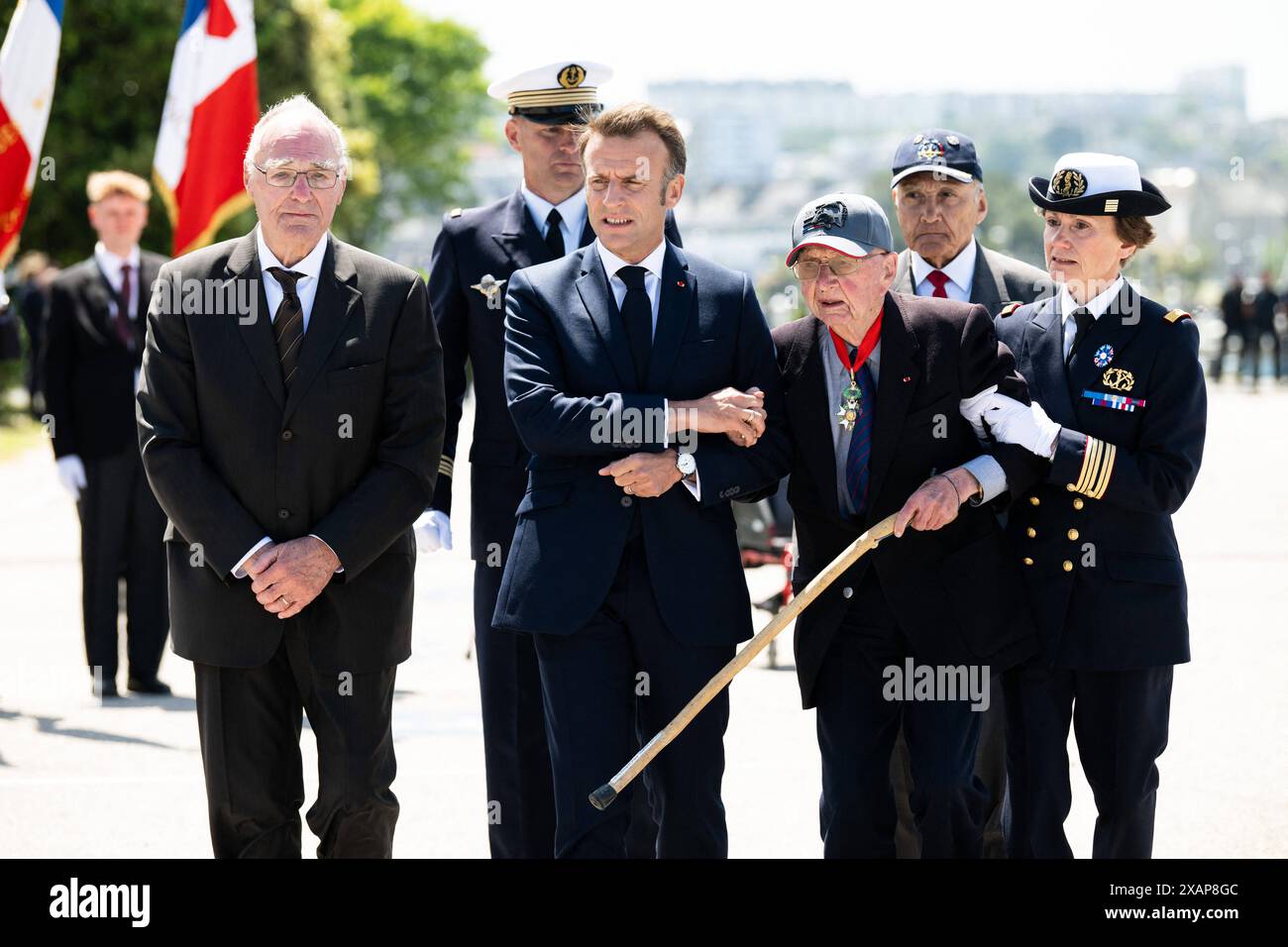 Emmanuel Macron and a veteran lay a wreath of flowers in tribute ...