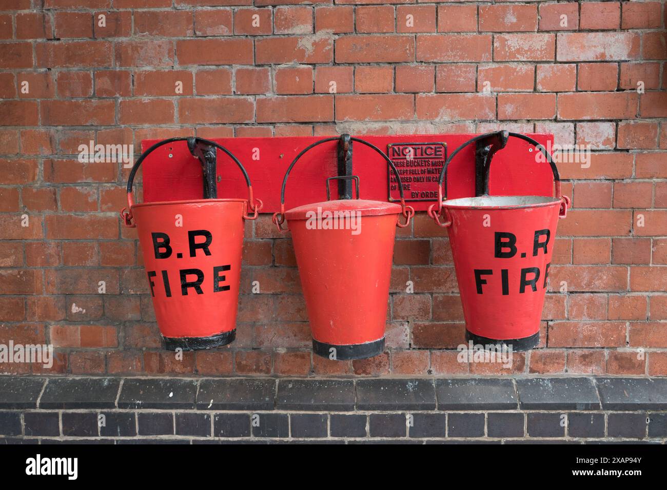 Three red fire buckets hanging on a brick wall at preserved historic ...