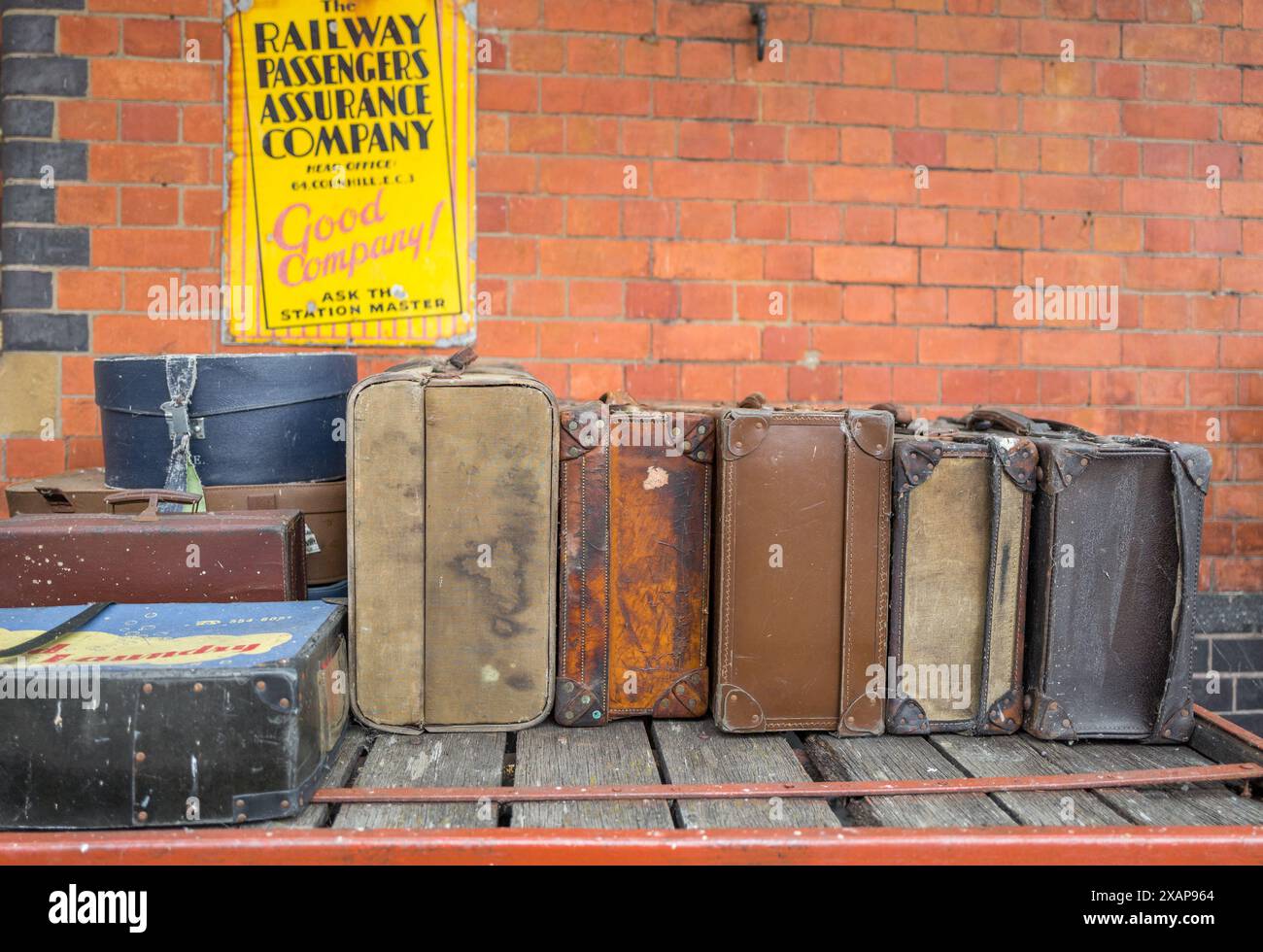 Old leather and canvas suitcases stacked onto railway station trolleys ...