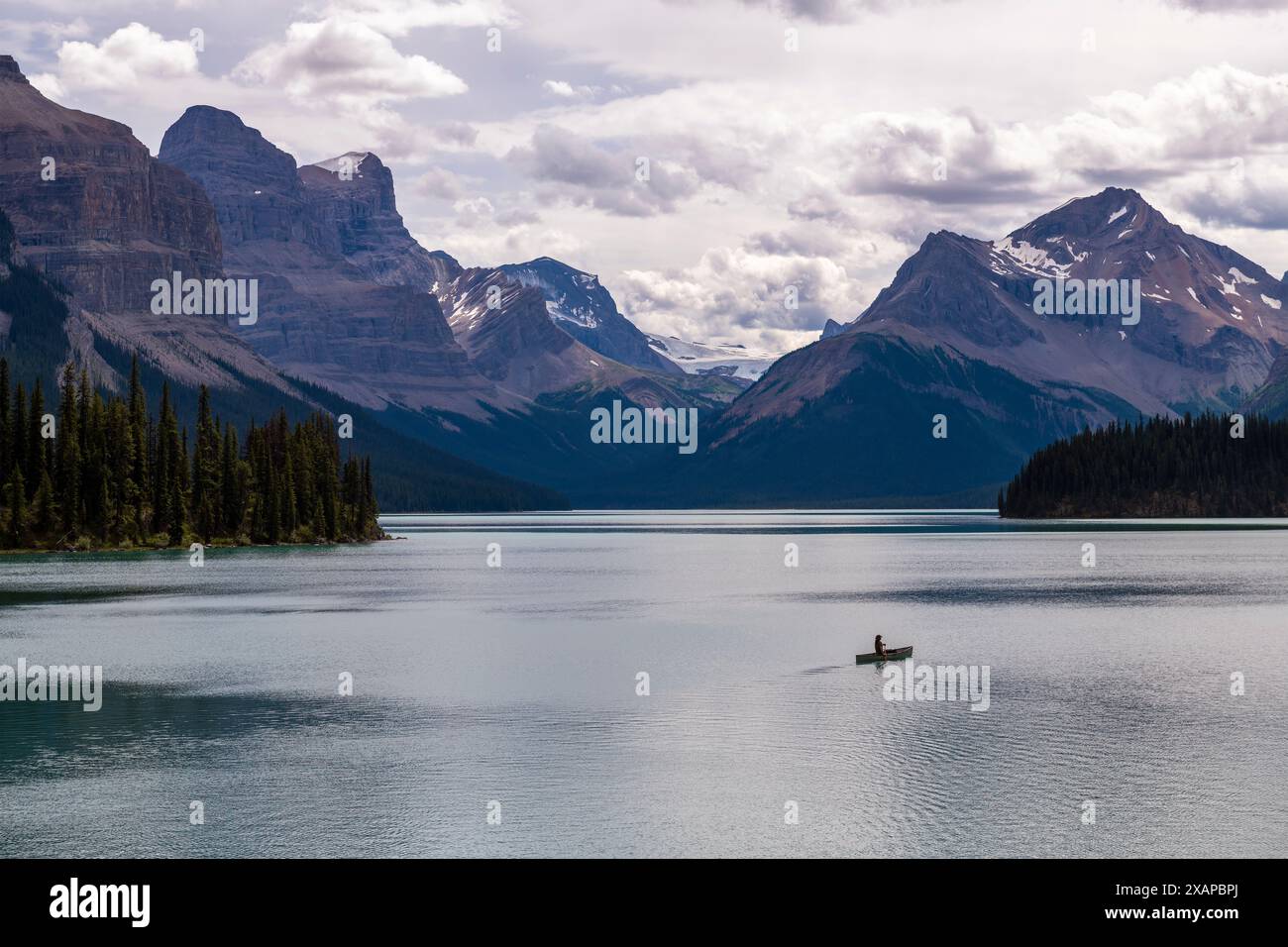 One man in the middle of nature, in a canoe on Maligne Lake, seen from ...