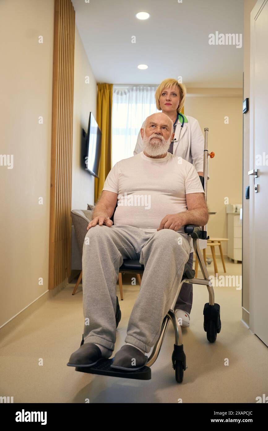 Doctor takes patient out of room in wheelchair Stock Photo - Alamy