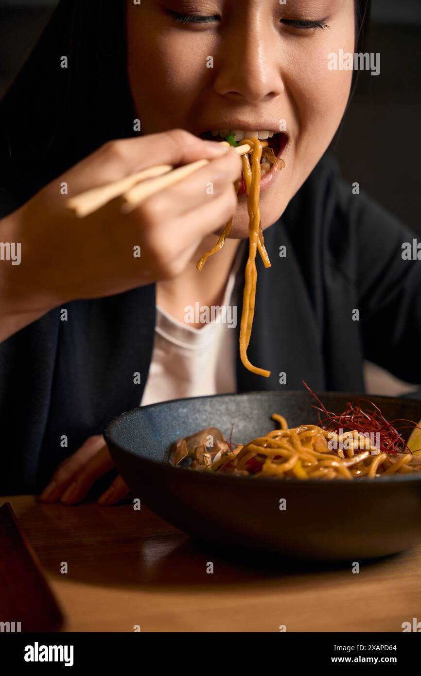 Close-up young Asian woman eating noodles in ginger-honey sauce with ...
