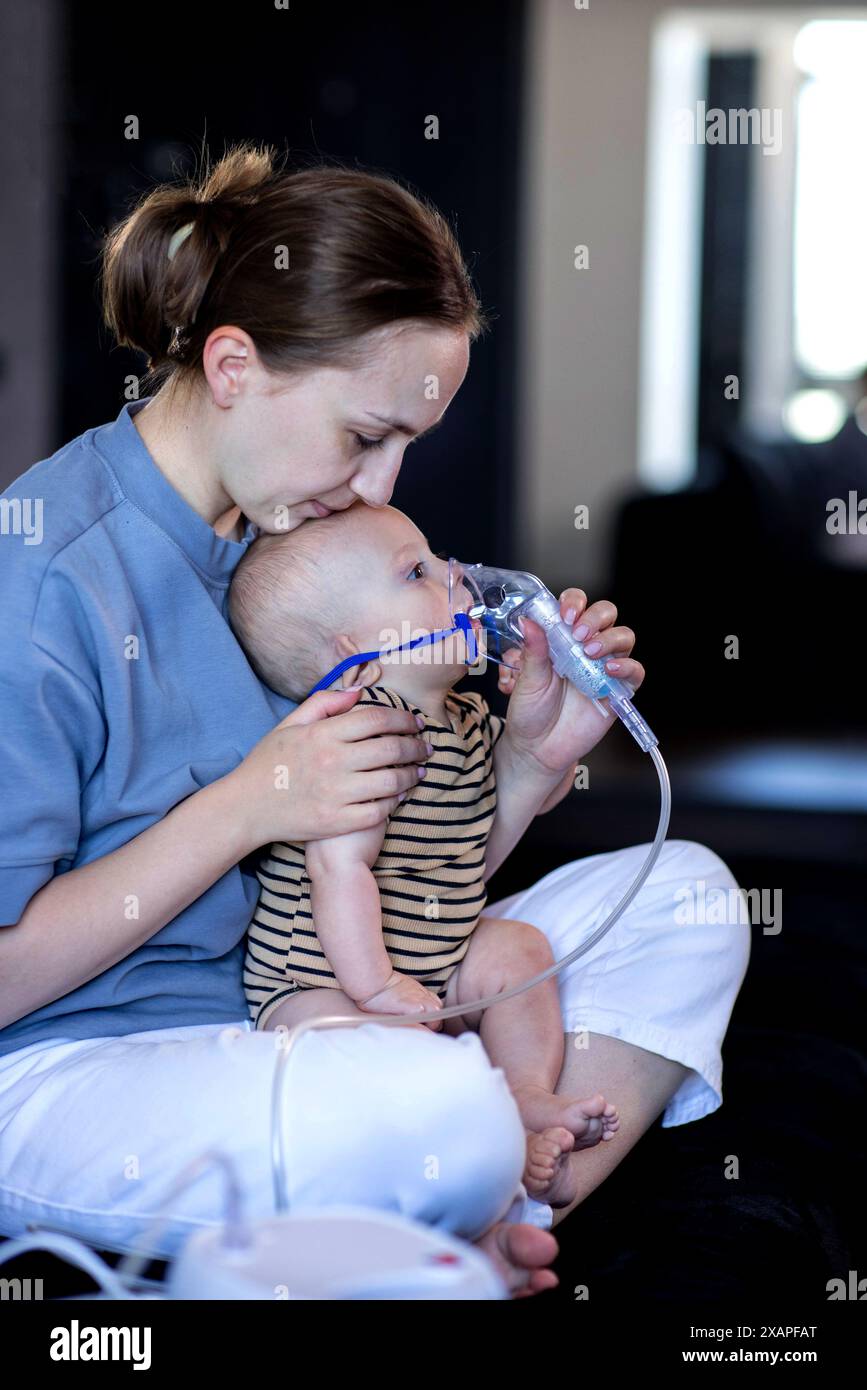 Mom giving nebulizer breathing treatment to sick infant baby at home ...