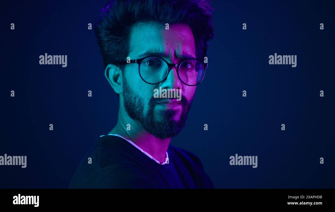 Close up male portrait in neon ultraviolet blue background Indian man ...