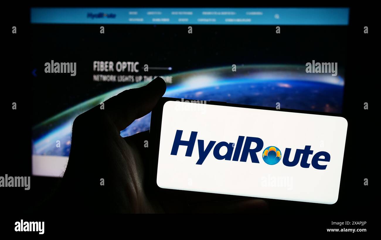 Person holding smartphone with logo of fiber company HyalRoute ...