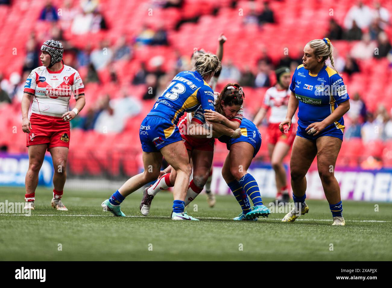 Emily Rudge of St Helens is tackled by Leeds Rhinos players during the ...