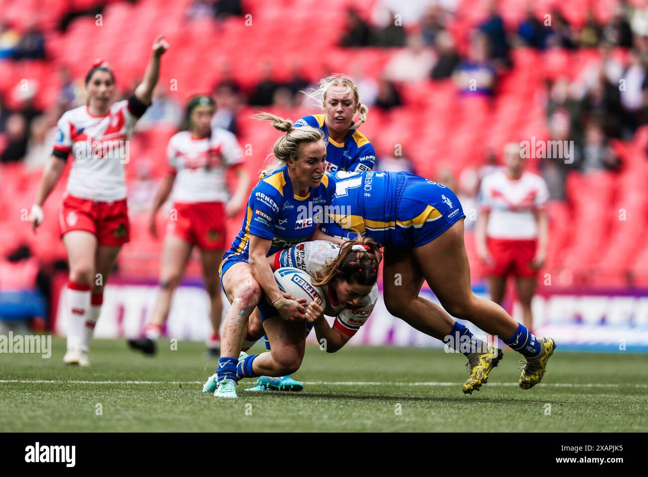 Emily Rudge of St Helens is tackled by Leeds Rhinos players during the ...