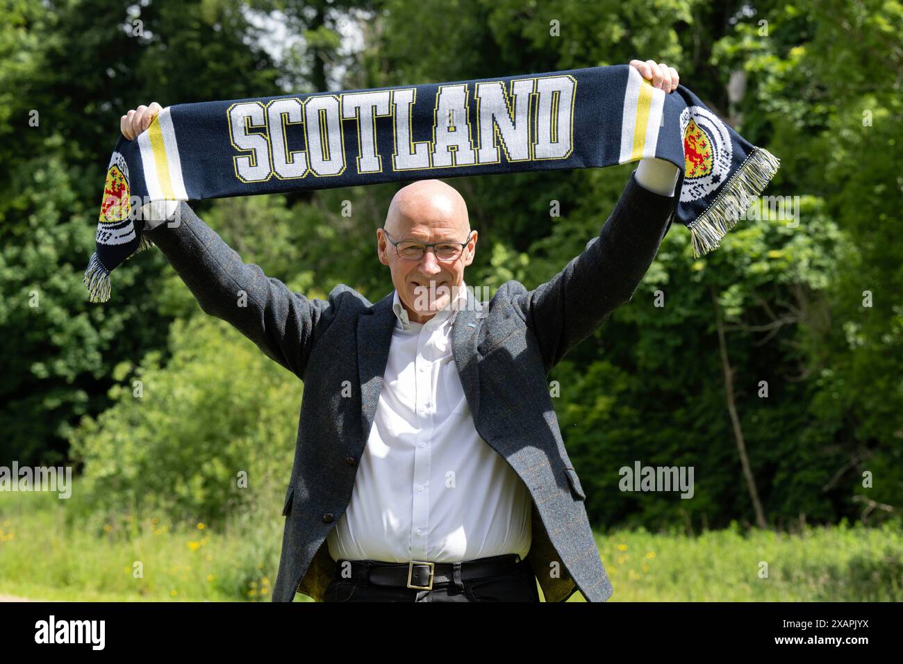 First Minister John Swinney holding up a Scotland scarf during a visit ...