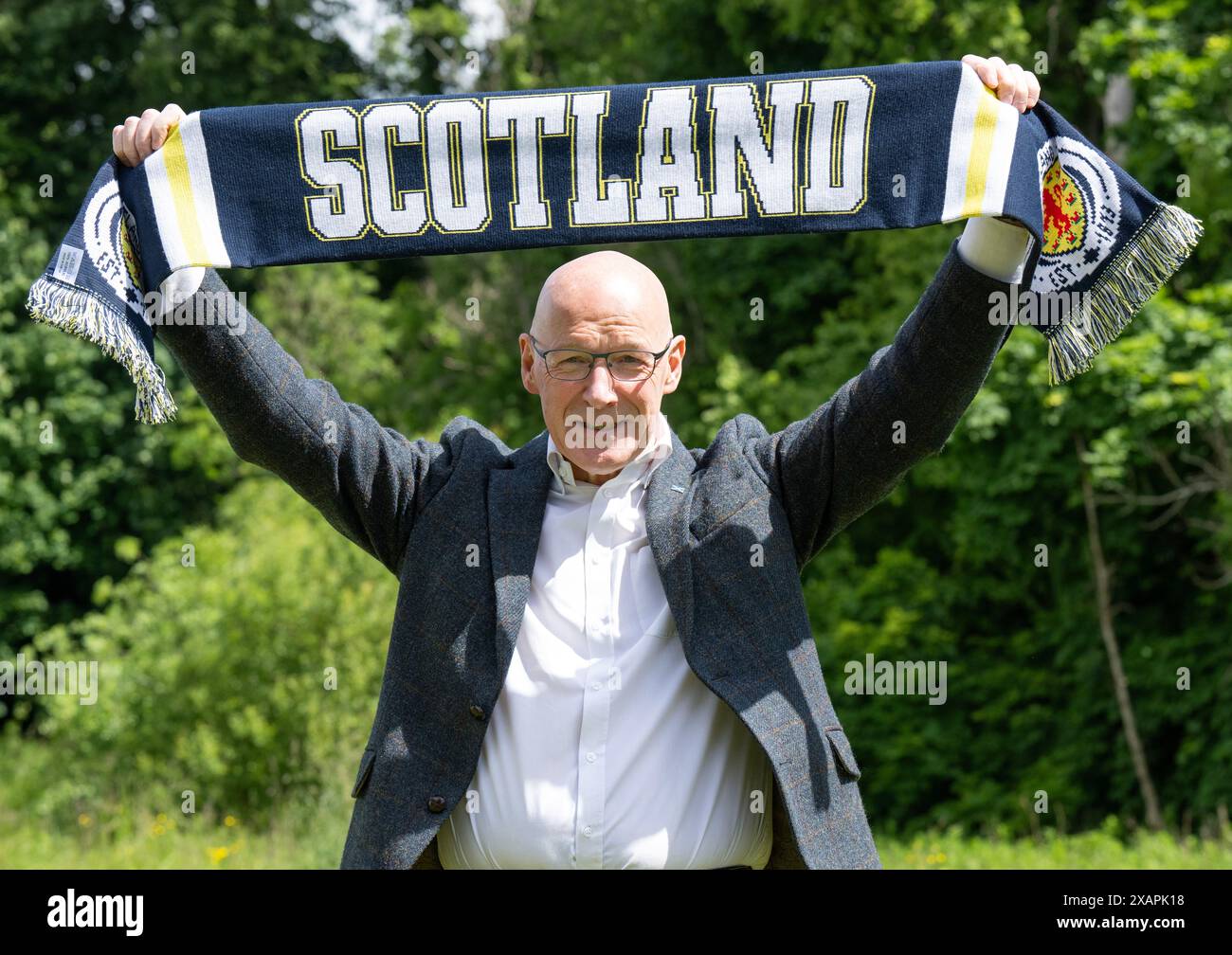 First Minister John Swinney holding up a Scotland scarf during a visit ...