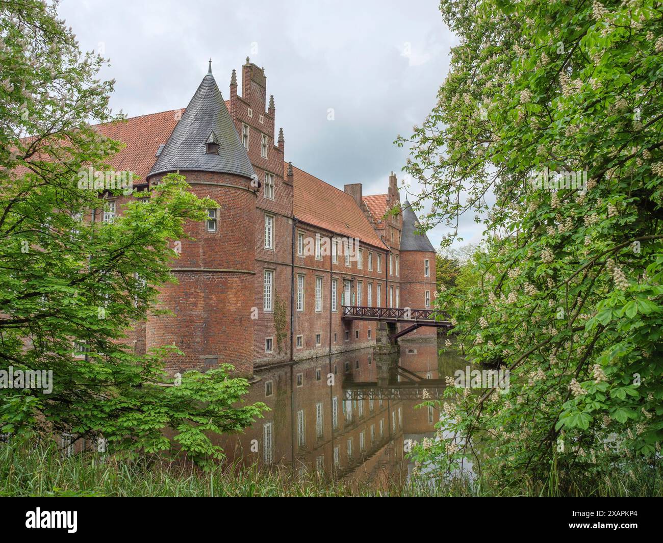 Historic red brick castle with bridge and towers, surrounded by dense ...