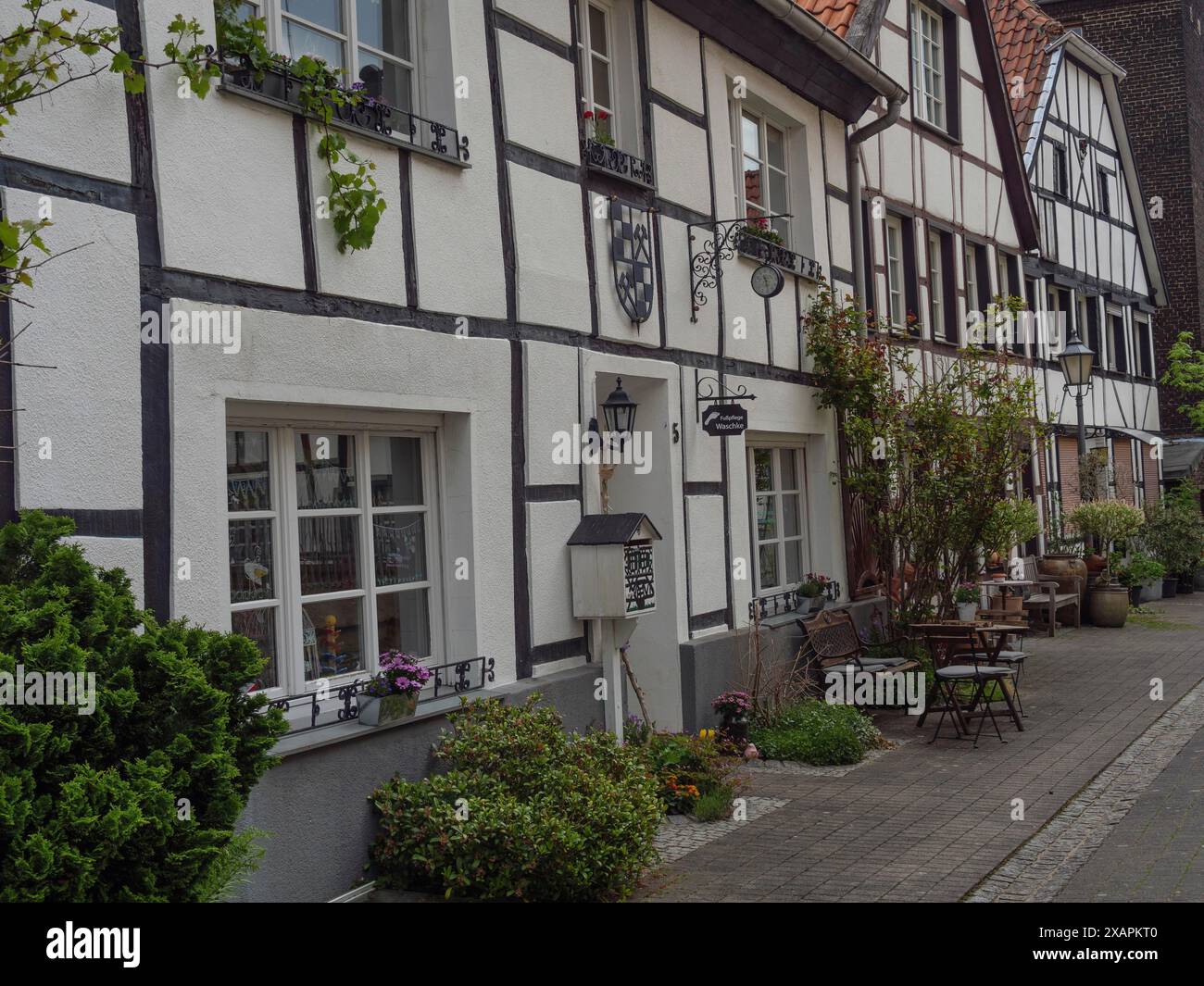 Quiet street with traditional half-timbered houses and numerous plants ...