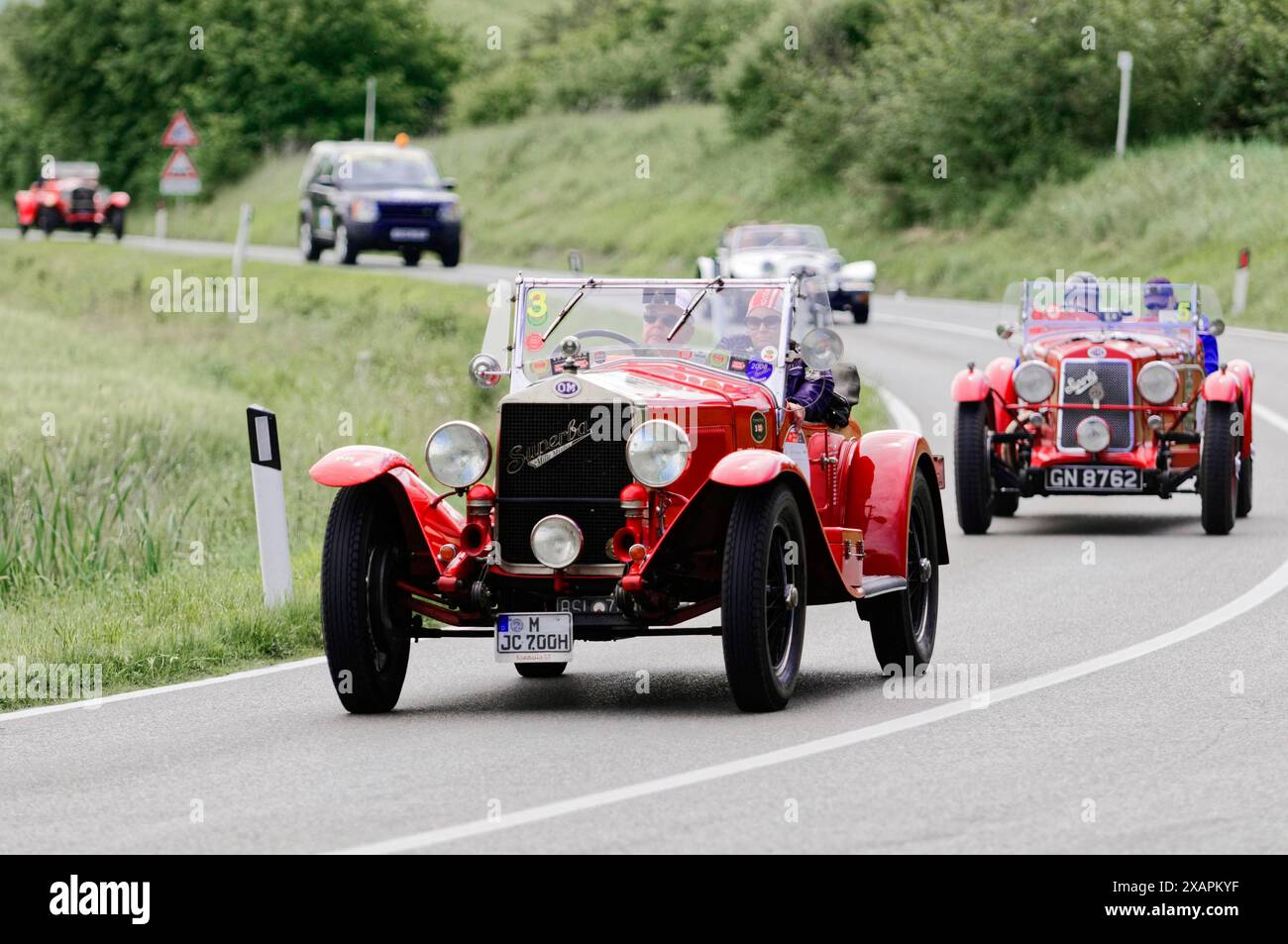 Racing car in a classic car rally on a winding country road, surrounded ...