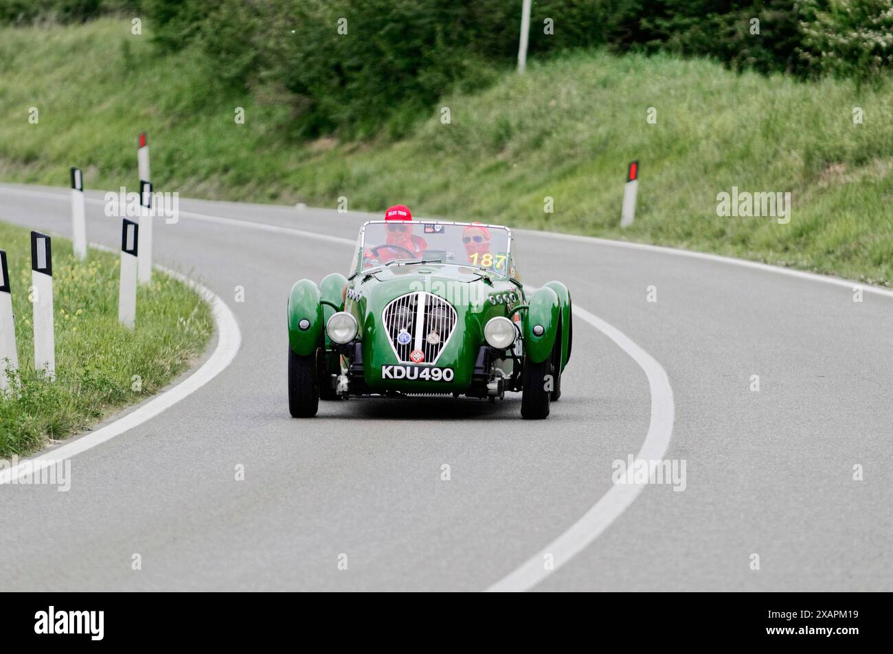 Green classic car on winding track, with racing number and driver in ...