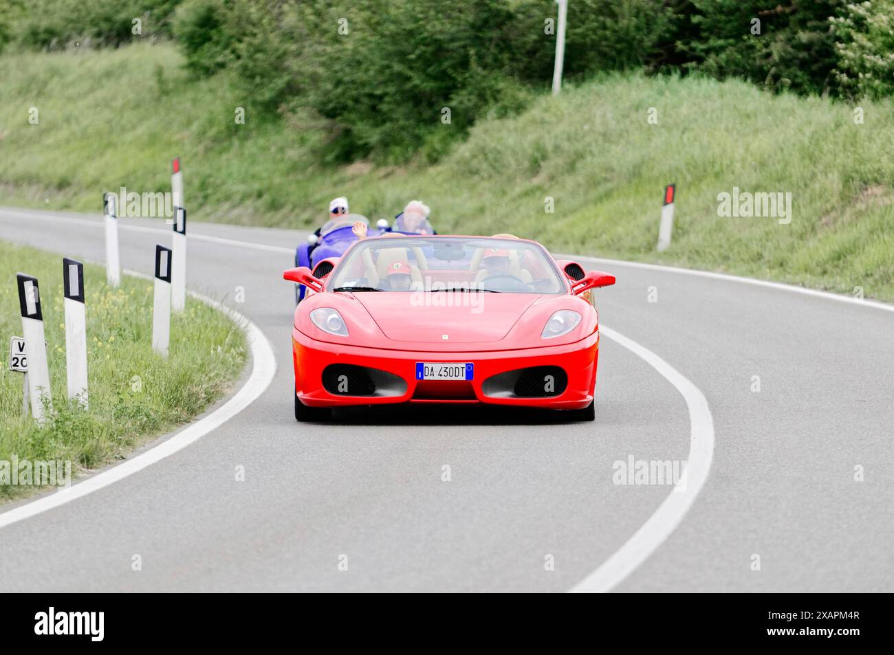Red super sports car drives fast through a winding country road ...