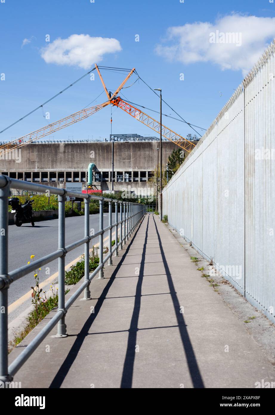 Foothpath with shadow sandwiched between a metal fence and metal rails ...