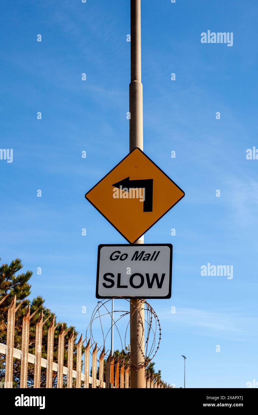 Go Slow and Left Turn road signs on a lamp post near to a road and ...