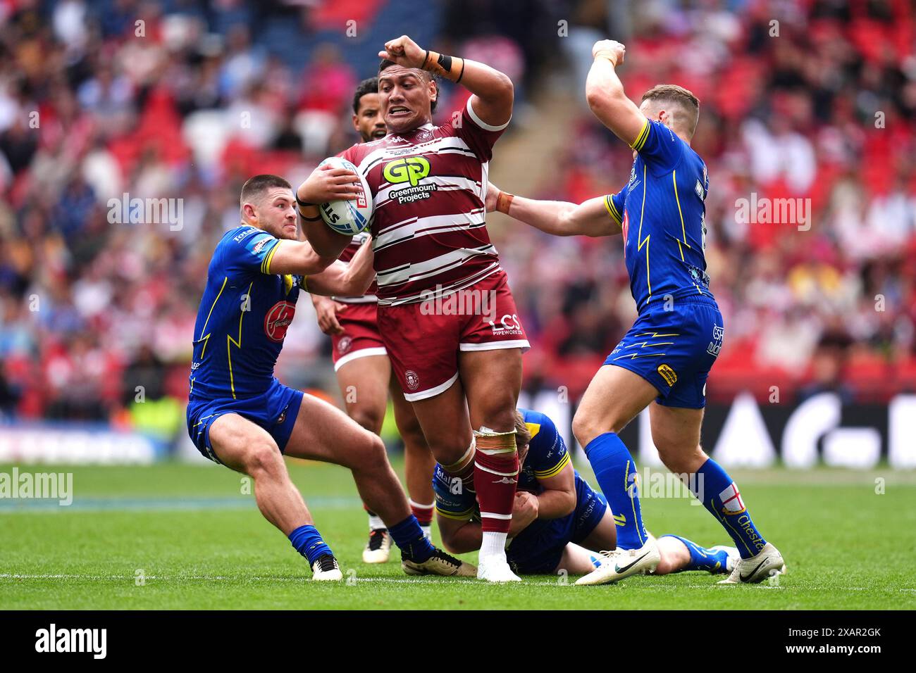 Wigan Warriors' Patrick Mago (centre) is tackled by Warrington Wolves ...