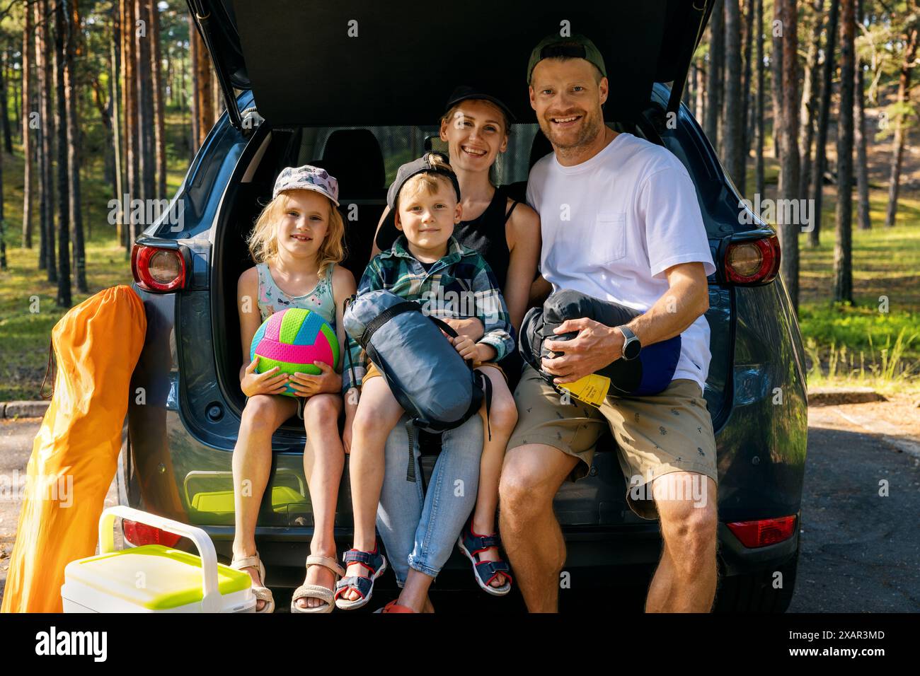 happy family with kids sitting in car trunk with camping supplies at ...