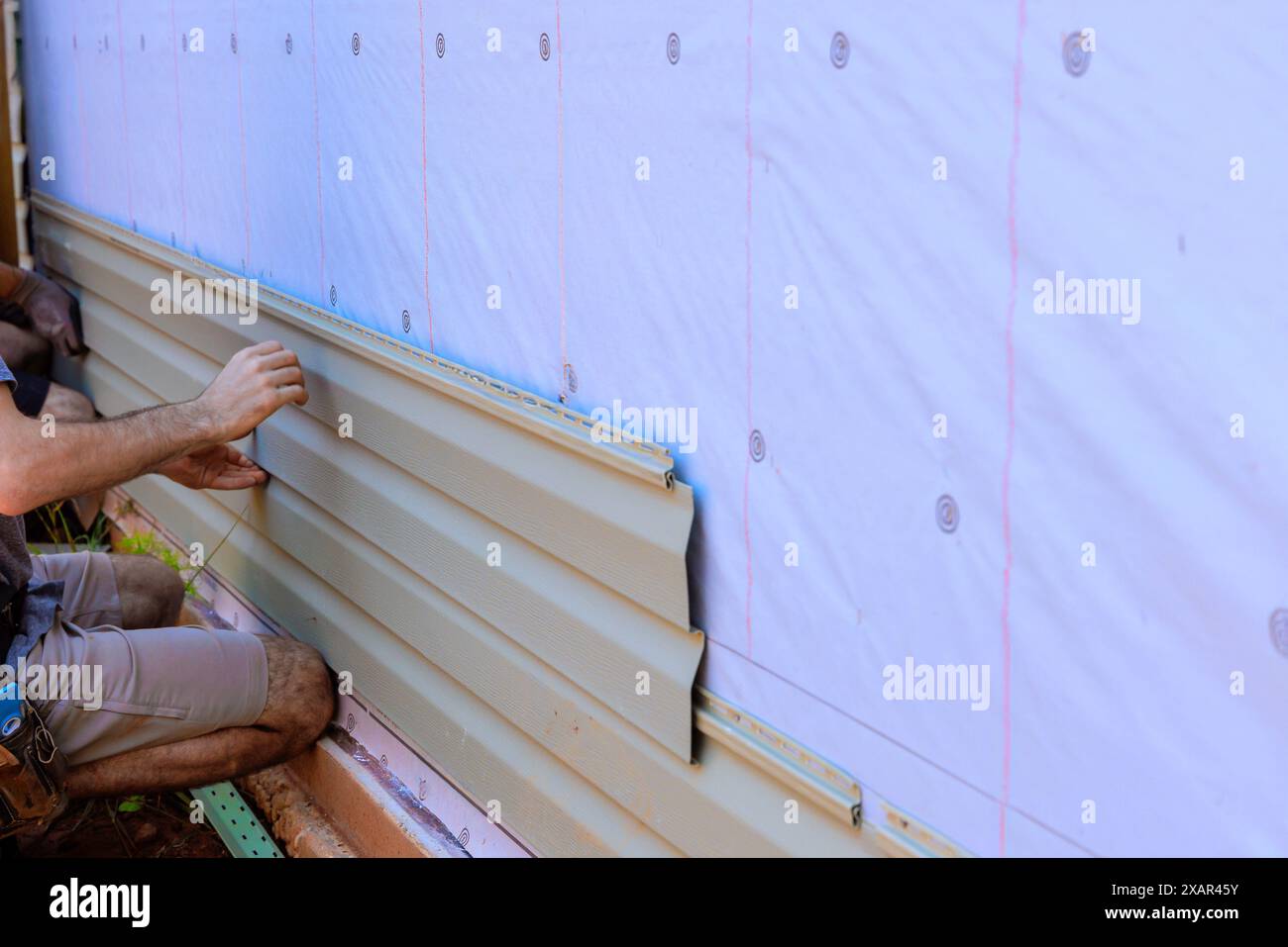 During construction of new home, handyman installs vinyl PVC siding ...