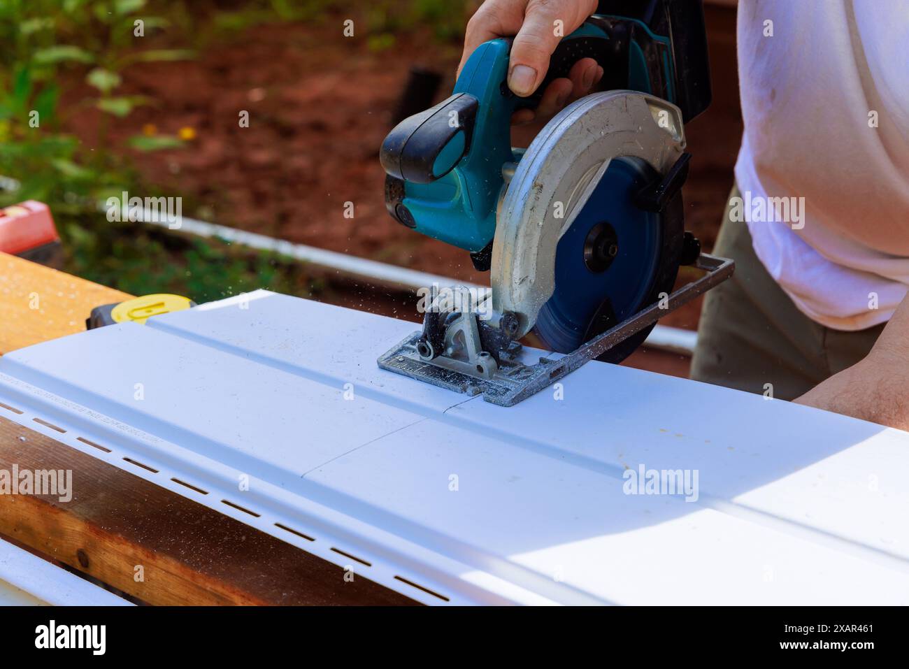 In process of construction, craftsman cuts vinyl siding panels to ...