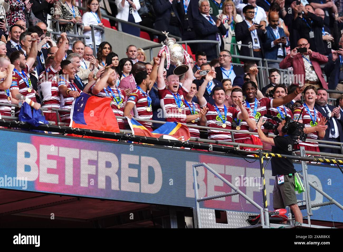 Wigan Warriors' Liam Farrell (centre) lifts the trophy with team-mates ...