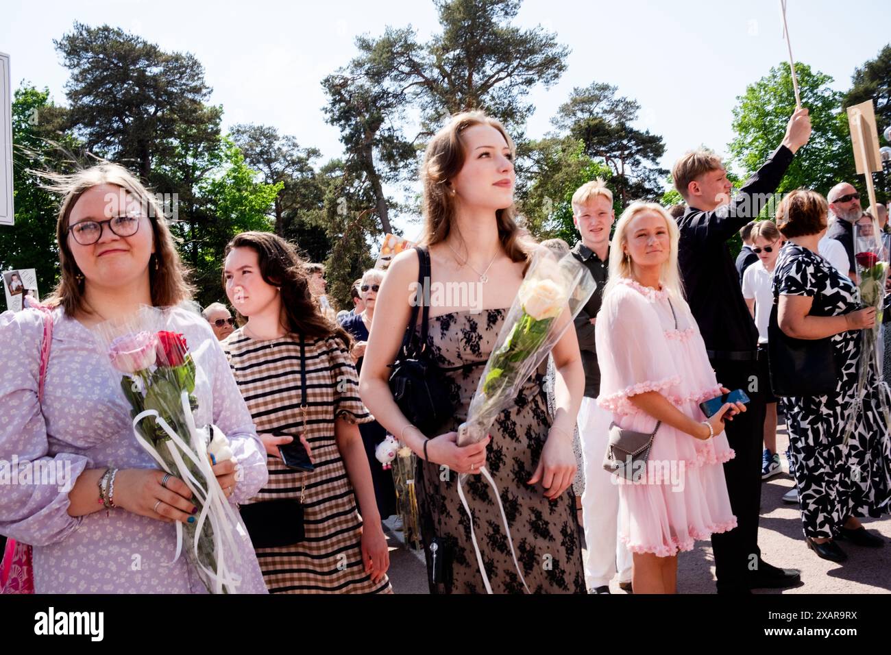 Friends wait with graduation roses outside the main school building for ...