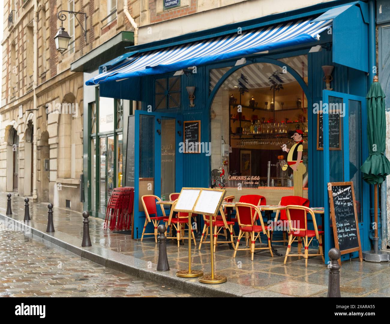A colourful Parisian cafe with blue exterior and red chairs in Place ...