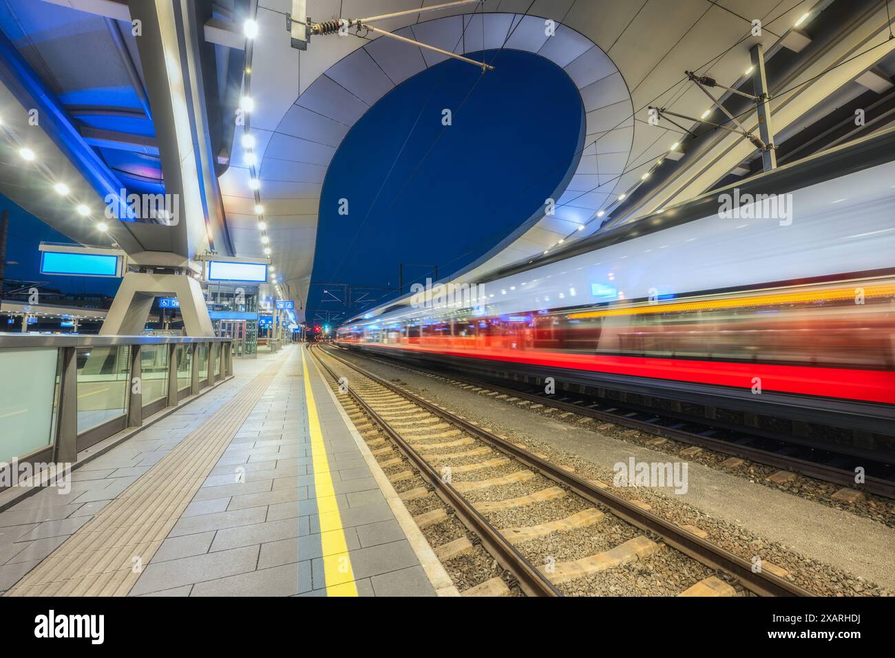 High-speed train at the illuminated railway station at night Stock ...