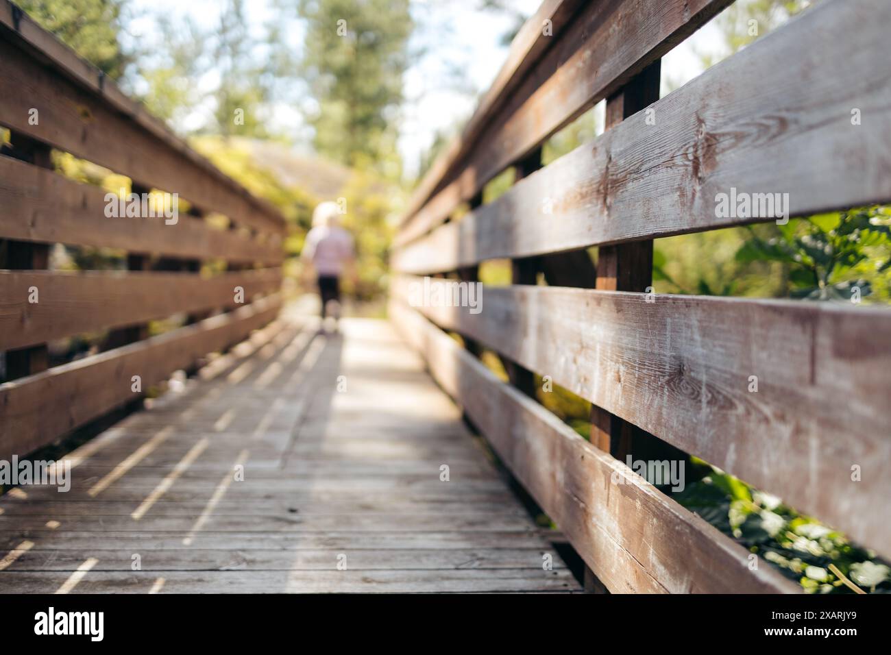 Closeup of part of wooden bridge with small child walking in the ...