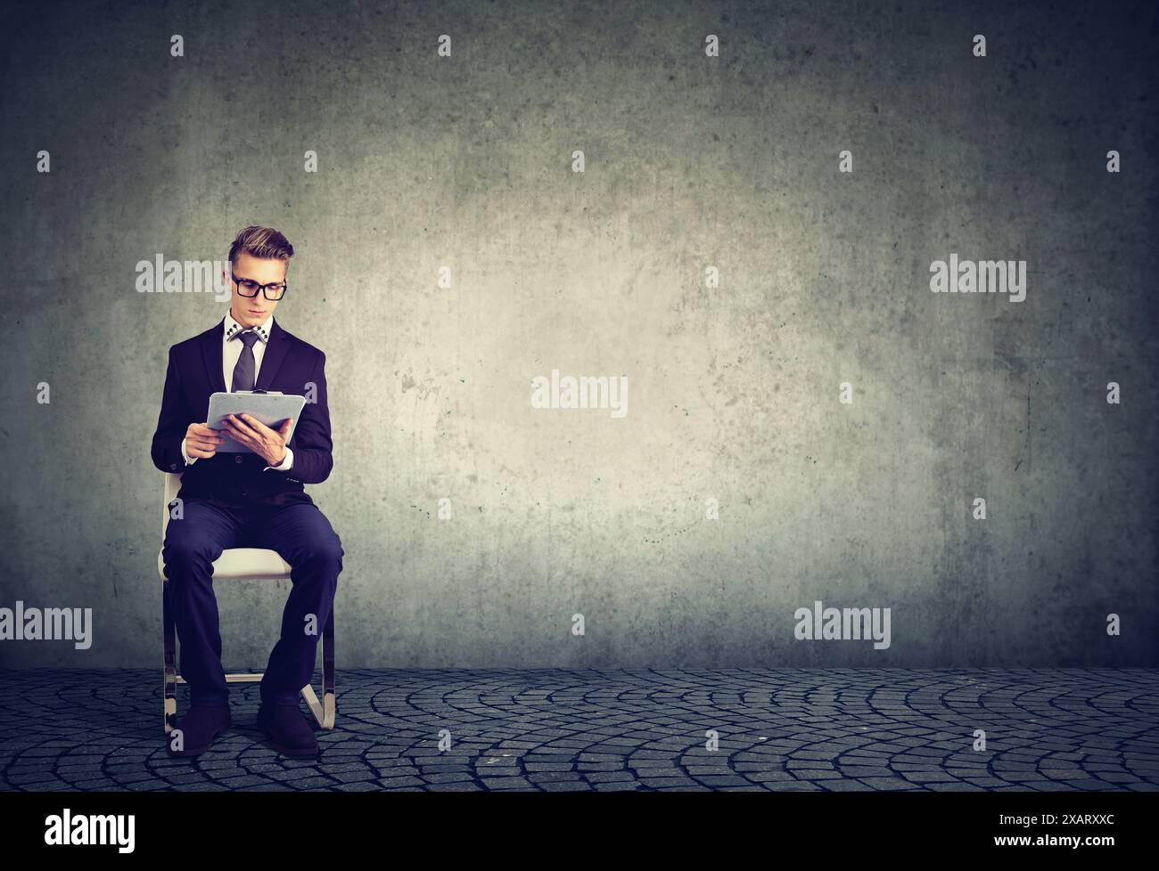 A job applicant sitting on a chair reading a contract Stock Photo - Alamy