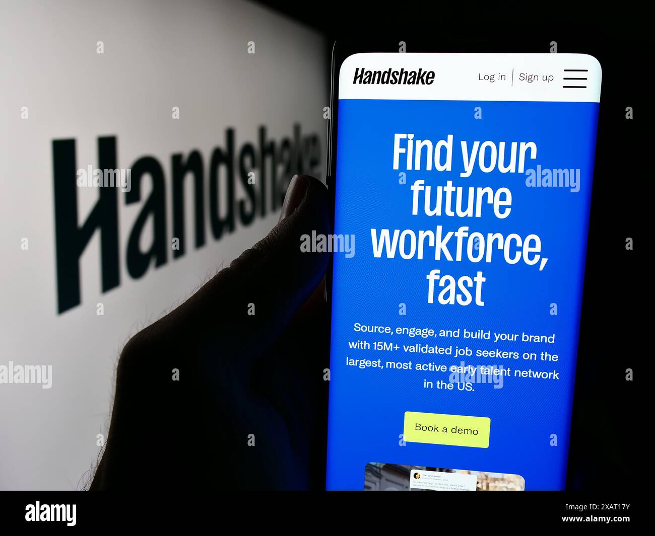 Person holding cellphone with webpage of US recruiting software company ...