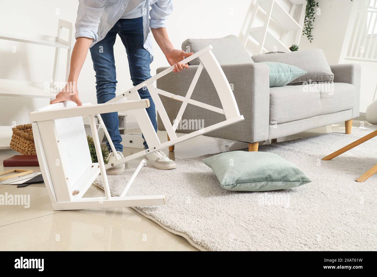 Woman taking broken chair from floor after earthquake at home Stock ...