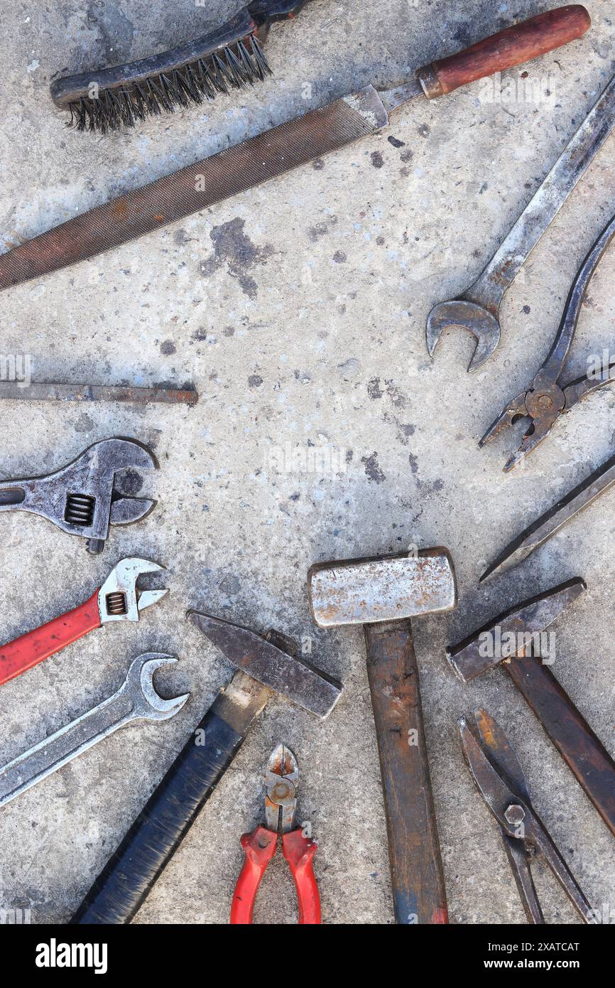 Old working tools on a concrete surface, top view. Hammers, flat file ...