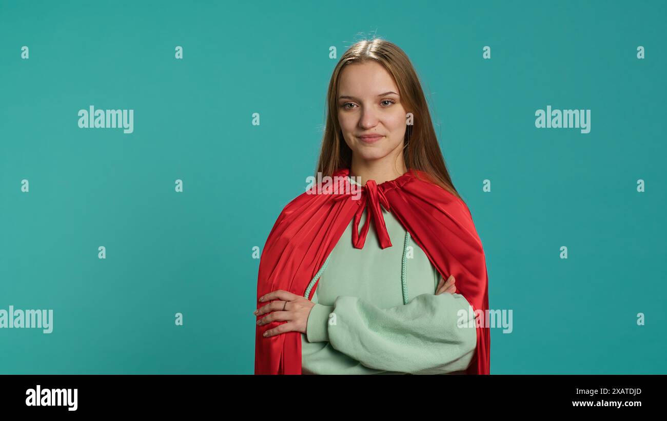 Smiling teenager portraying superhero wearing red cape, isolated over ...