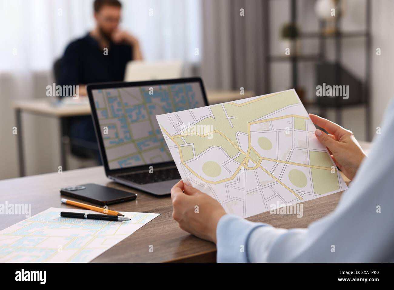 Cartographer working with cadastral maps at wooden table in office ...