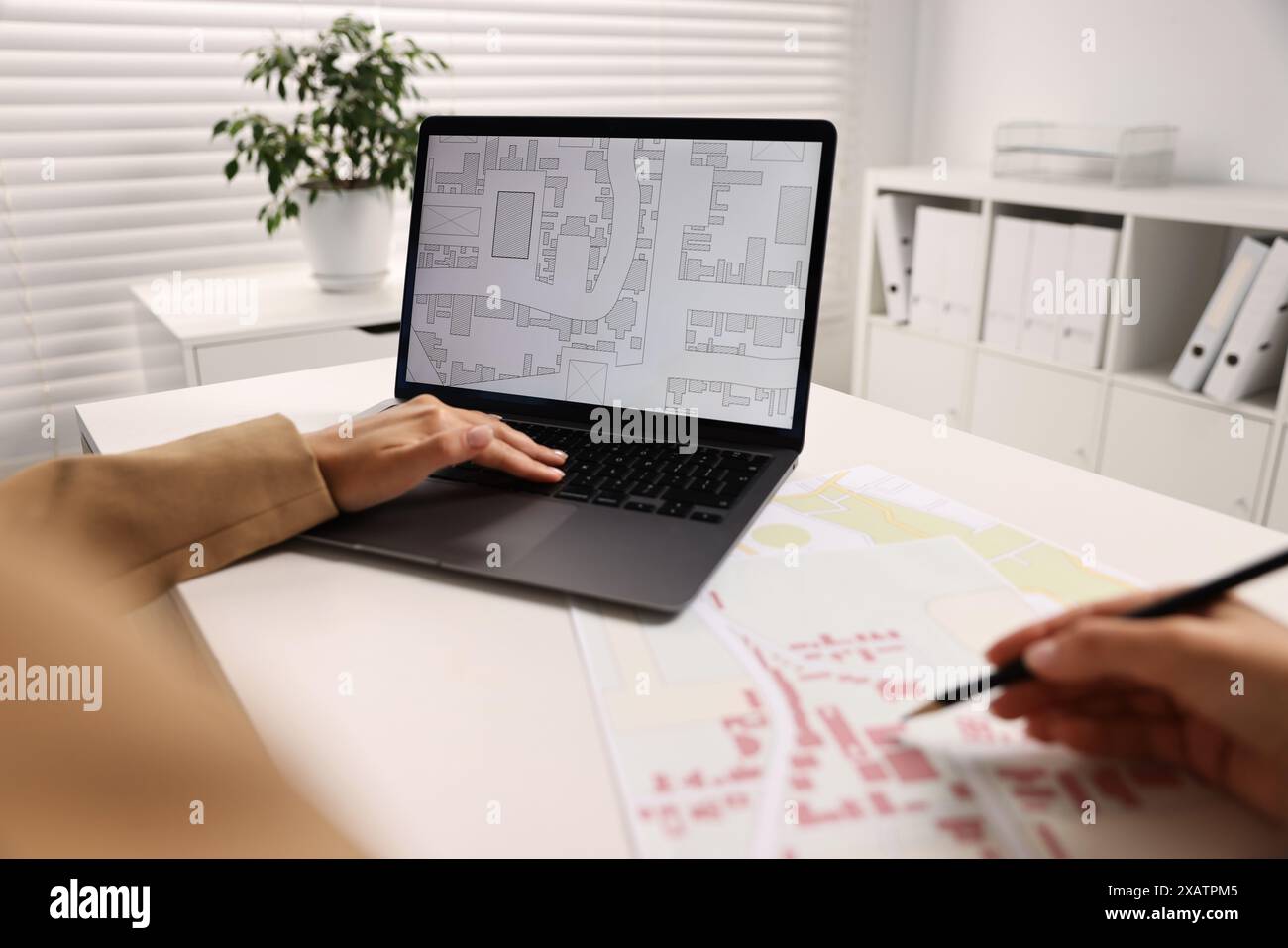 Cartographer working with cadastral map on laptop at white table in ...