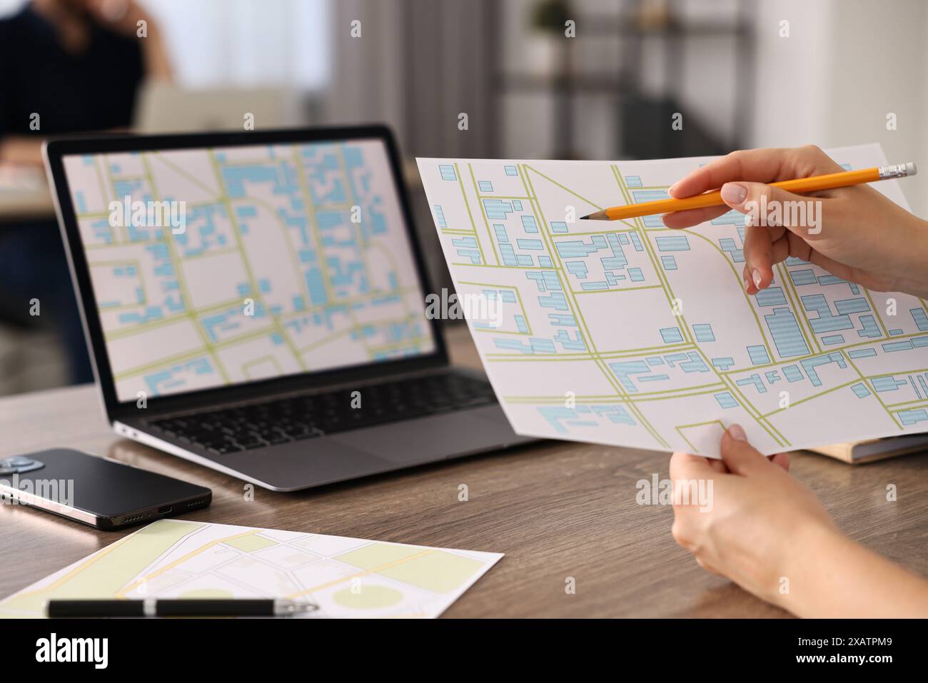 Cartographer working with cadastral maps at wooden table in office ...