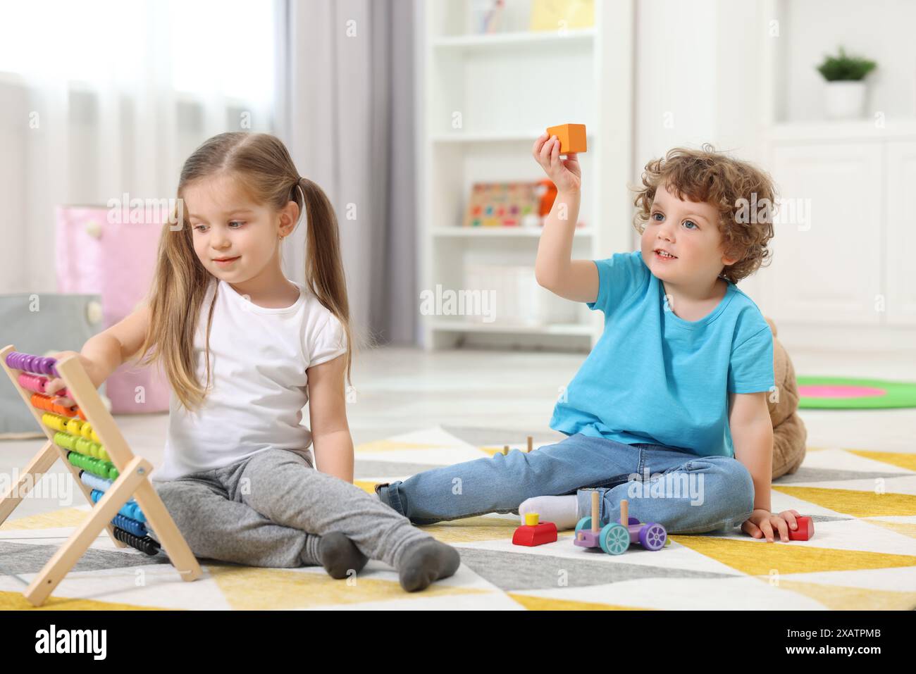 Cute little children playing with different toys on floor in ...
