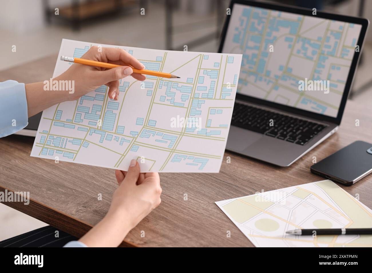 Cartographer working with cadastral maps at wooden table in office ...