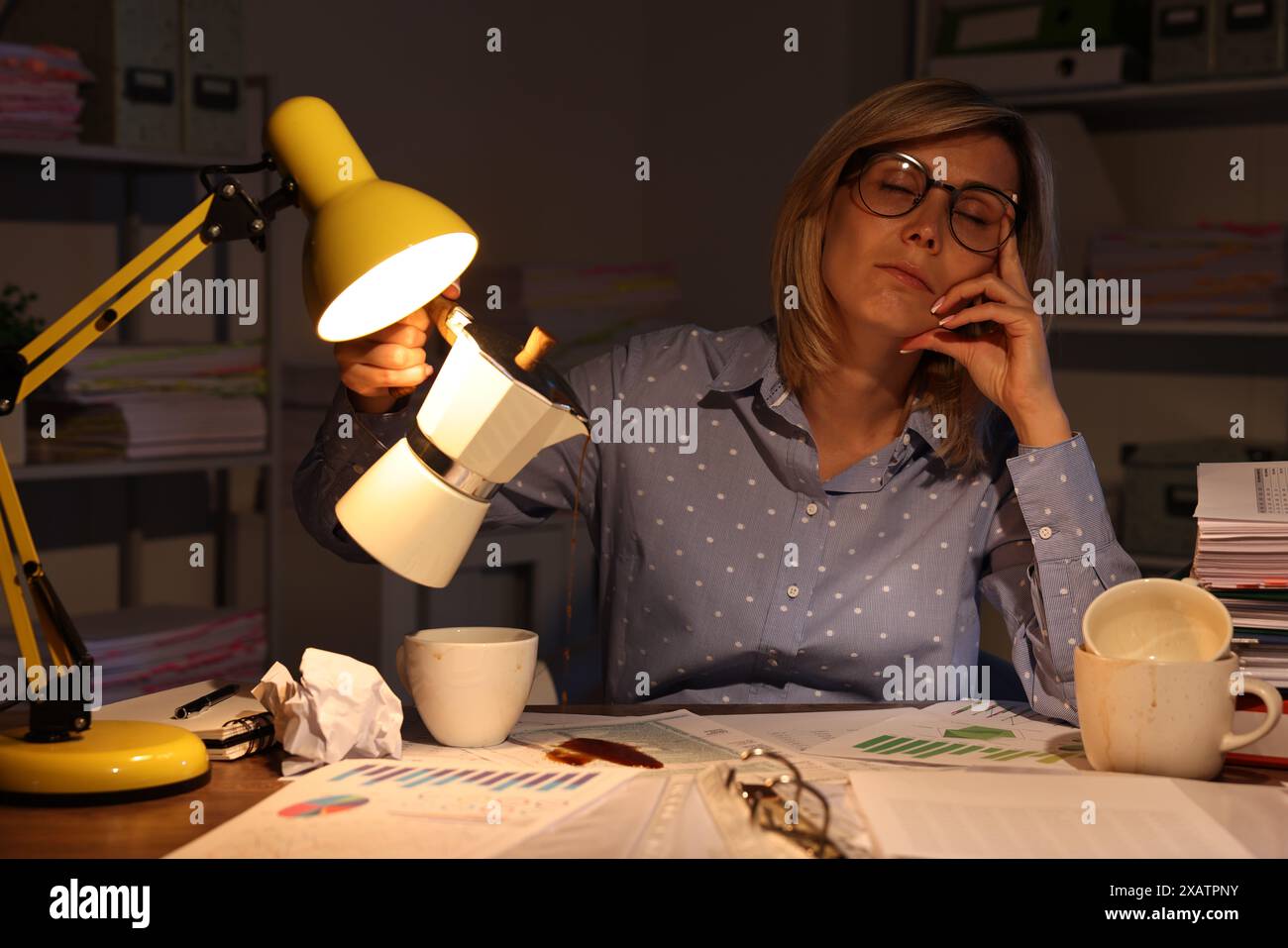 Overwhelmed woman pouring coffee onto documents while snoozing at ...