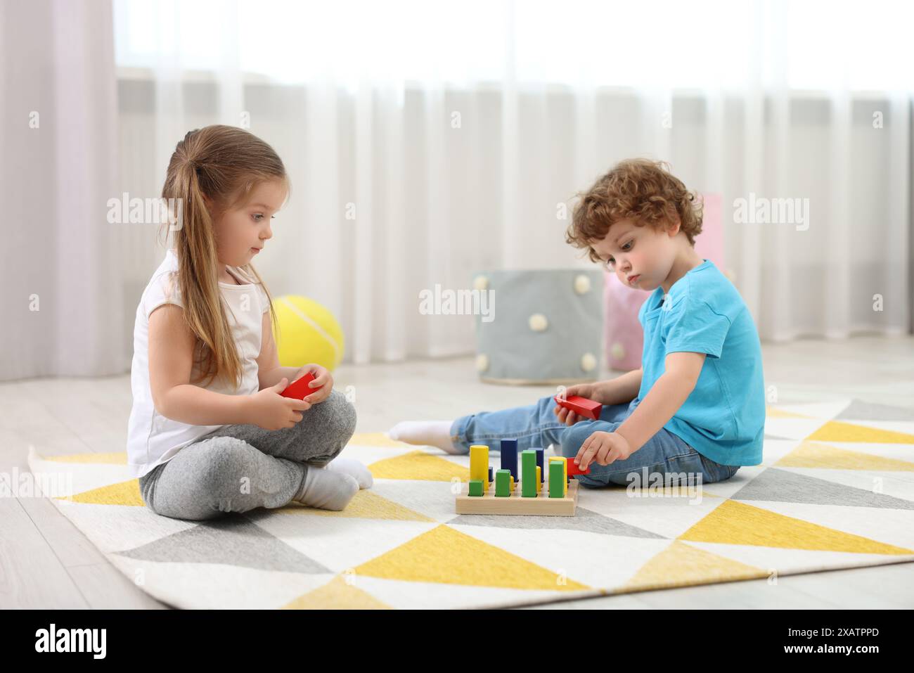 Cute little children playing with set of wooden geometric figures on ...